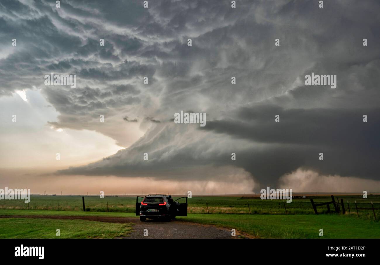A storm chaser s vehicle parked on a dirt road observing a massive ...