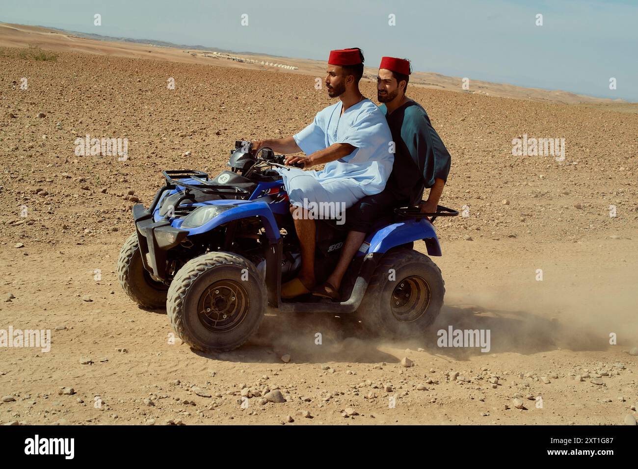 Two men in traditional attire enjoying a quad bike ride through a ...