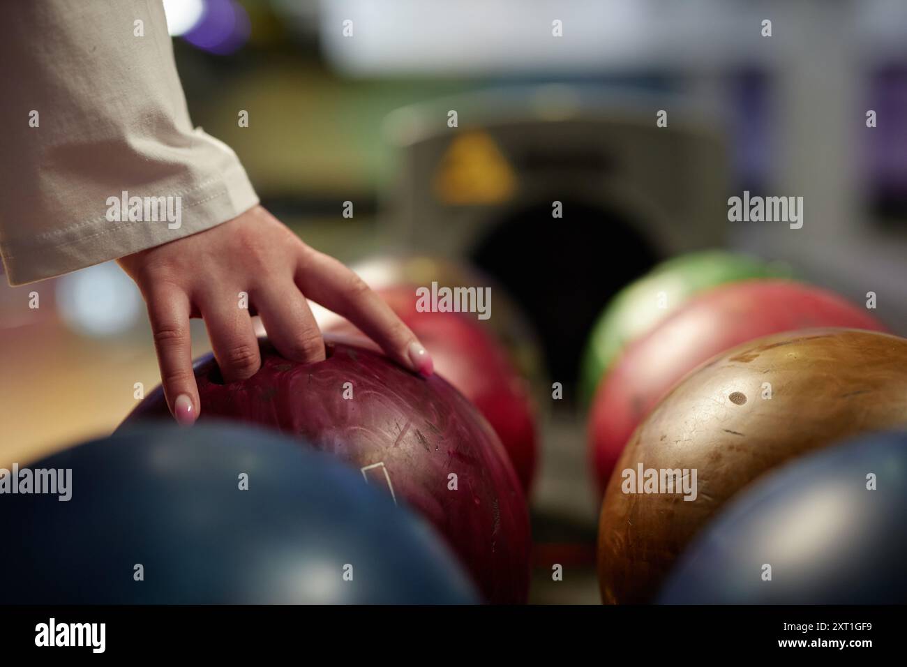 Hand reaching for vibrant bowling ball in colorful, well-lit bowling ...