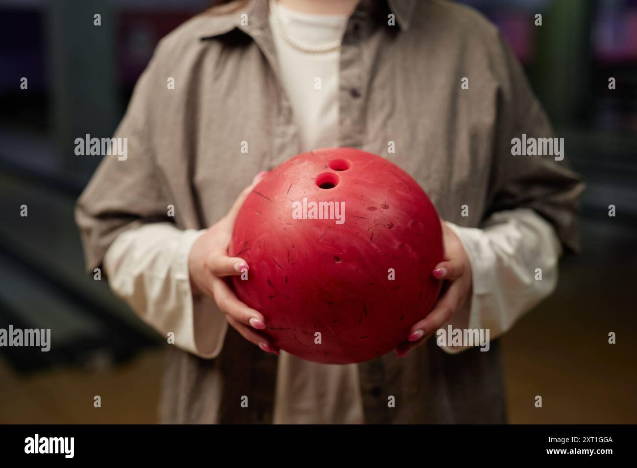 Person holding red bowling ball in bowling alley, preparing for game ...