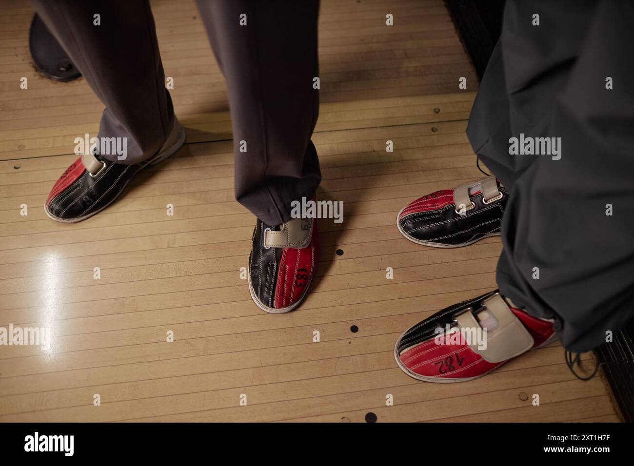 Pair of feet wearing bowling shoes standing on wooden bowling alley ...