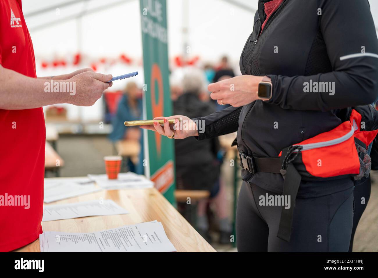 A person in a red shirt hands a pen to another in a black jacket at a ...