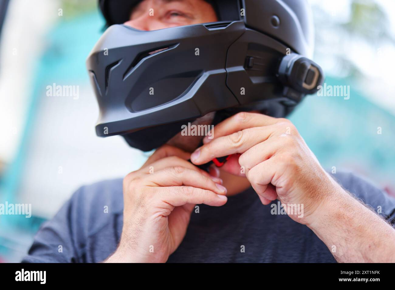 man fastens a black helmet on his head Stock Photo - Alamy
