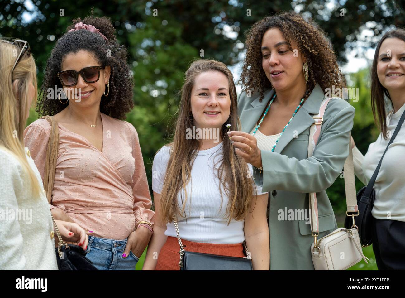 A group of women enjoying a conversation outdoors with trees in the ...