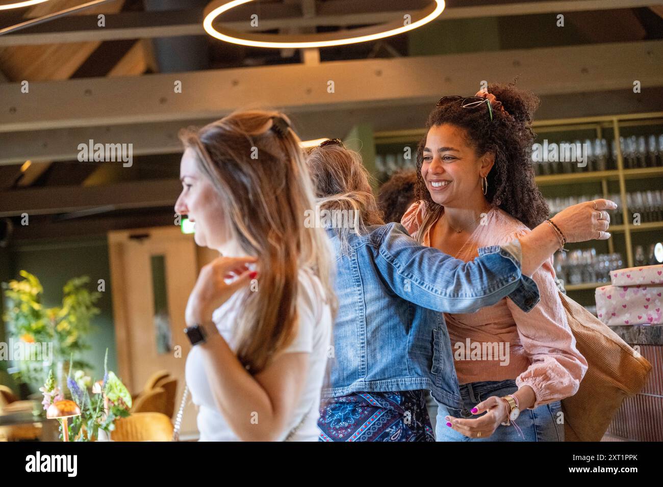 Joyful friends hugging and smiling at a casual indoor gathering ...