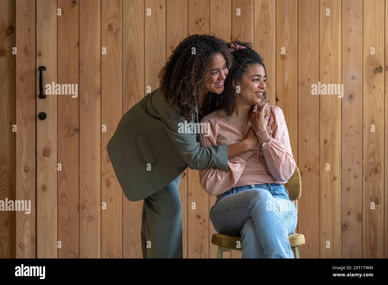 Two women share a joyful moment, with one standing and embracing the ...