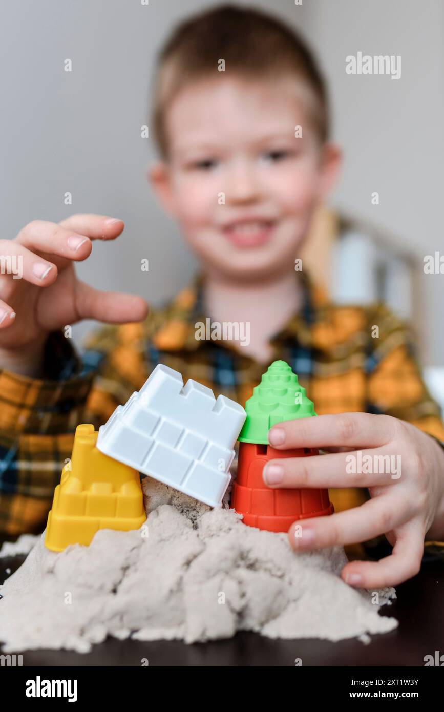 A good boy makes a tower of kinetic sand at home. The child plays in ...