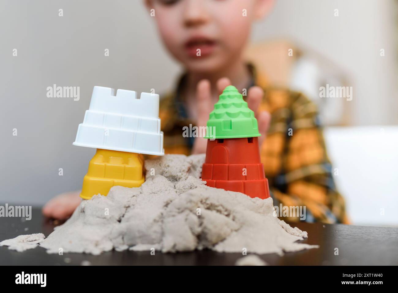 A good boy makes a tower of kinetic sand at home. The child plays in ...