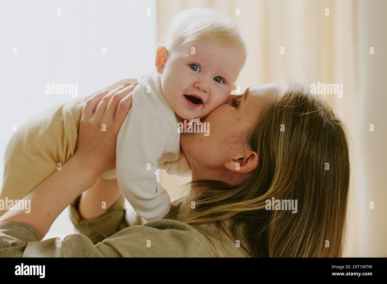 Smiling Mother Holding Baby and Kissing Cheek Stock Photo - Alamy