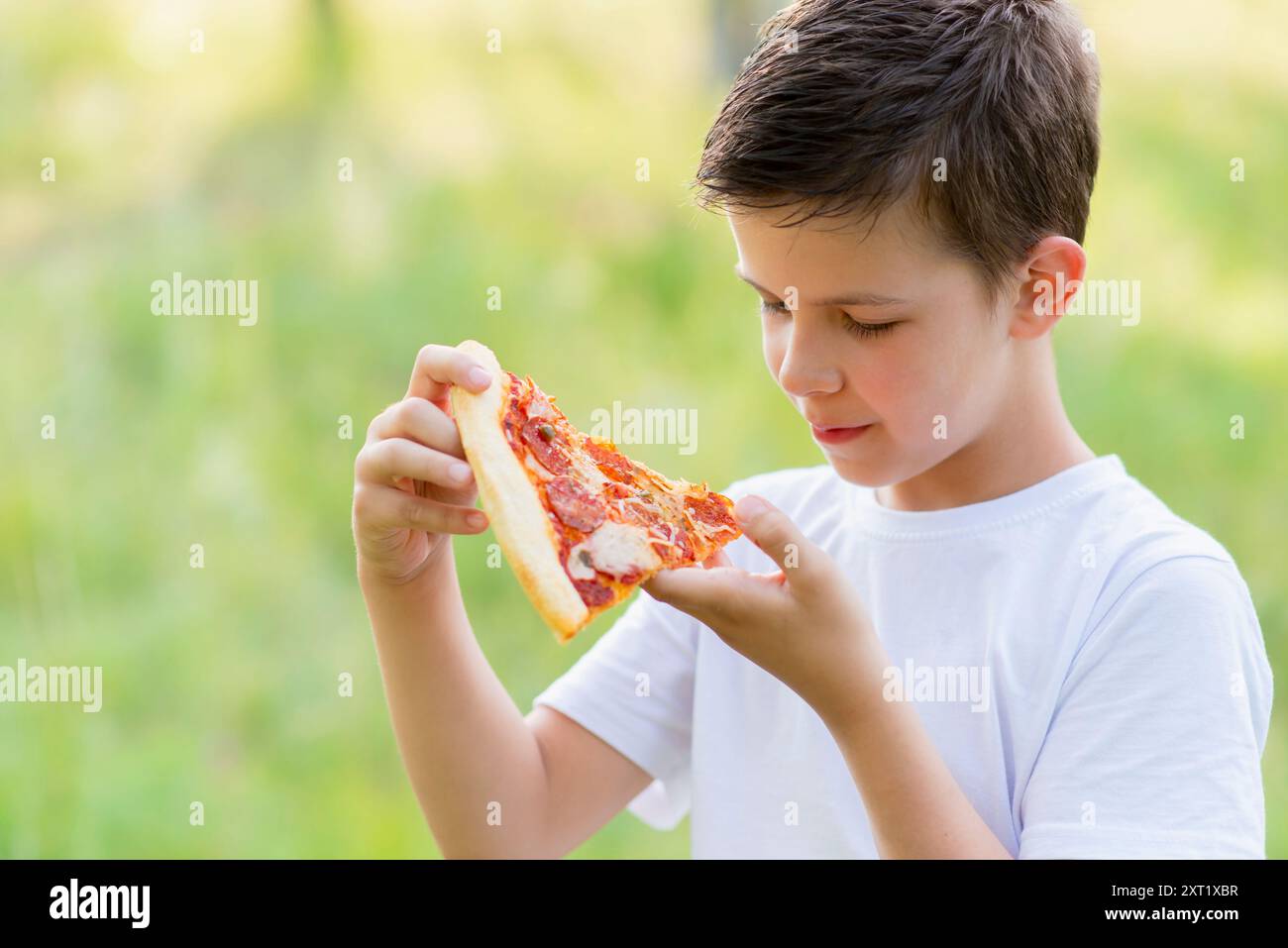 Cute boy eating pizza outdoors in summer Stock Photo - Alamy