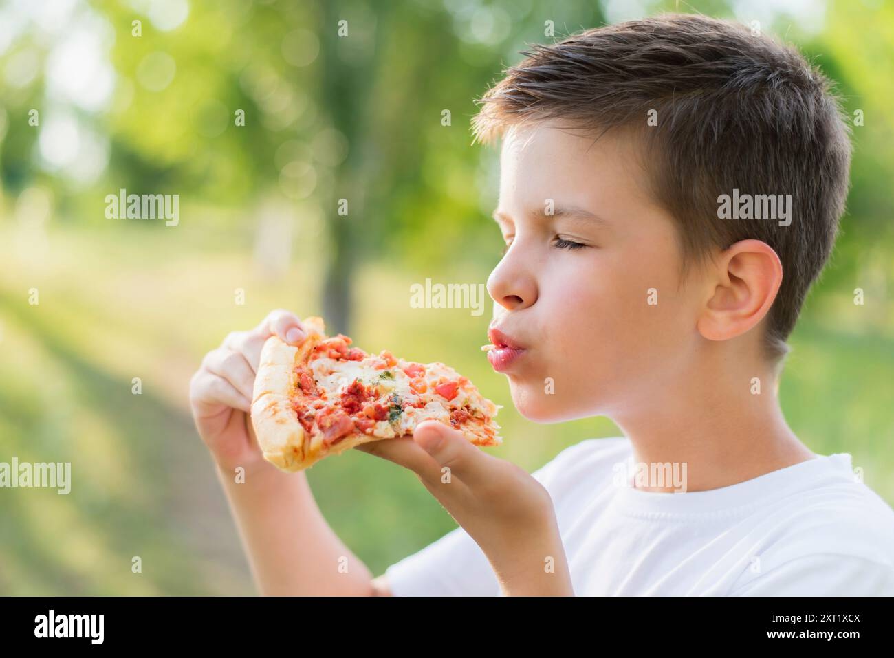 Cute boy eating pizza outdoors in summer Stock Photo - Alamy