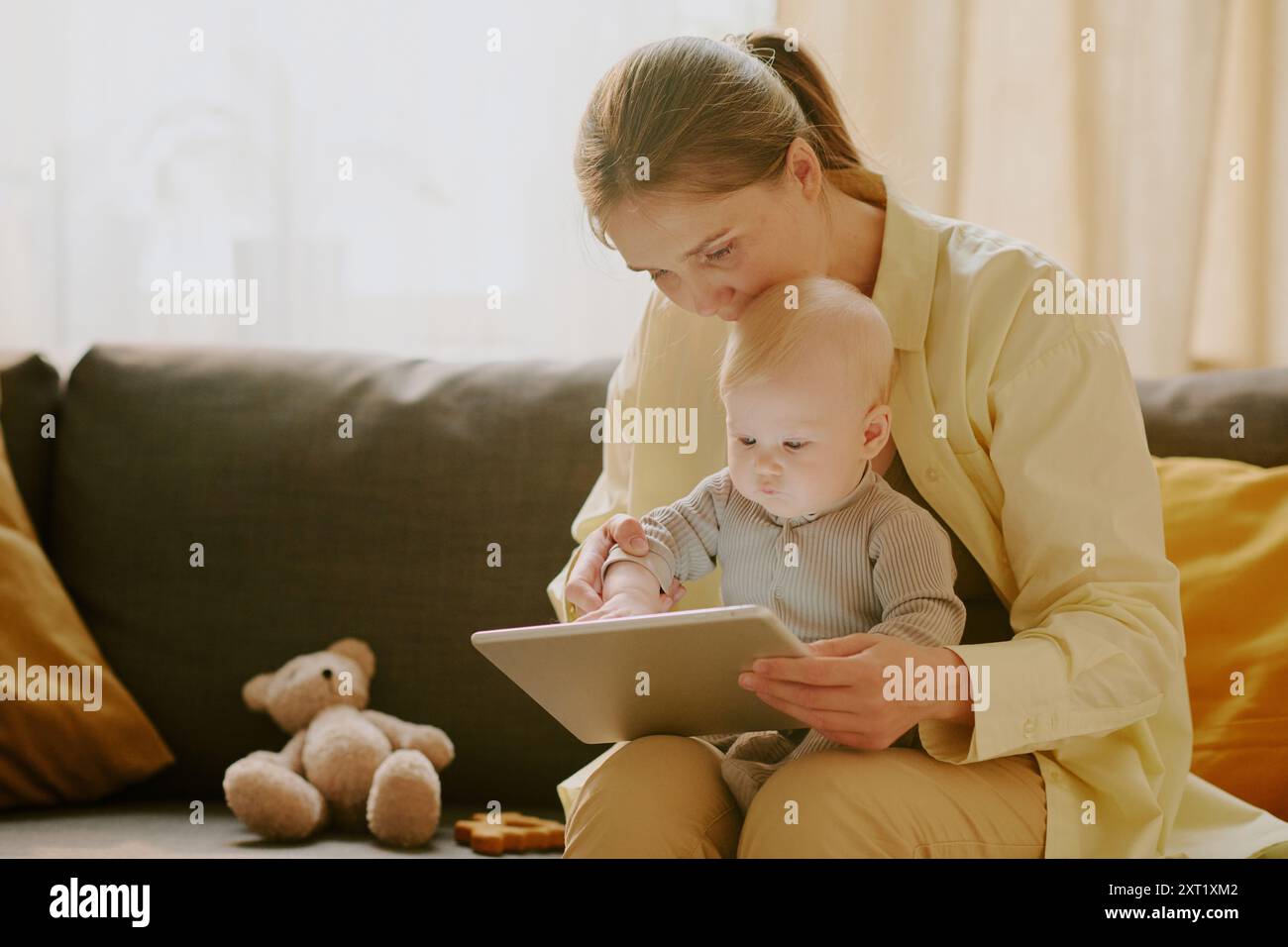 Mother and Baby Using Tablet While Sitting on Sofa Stock Photo - Alamy