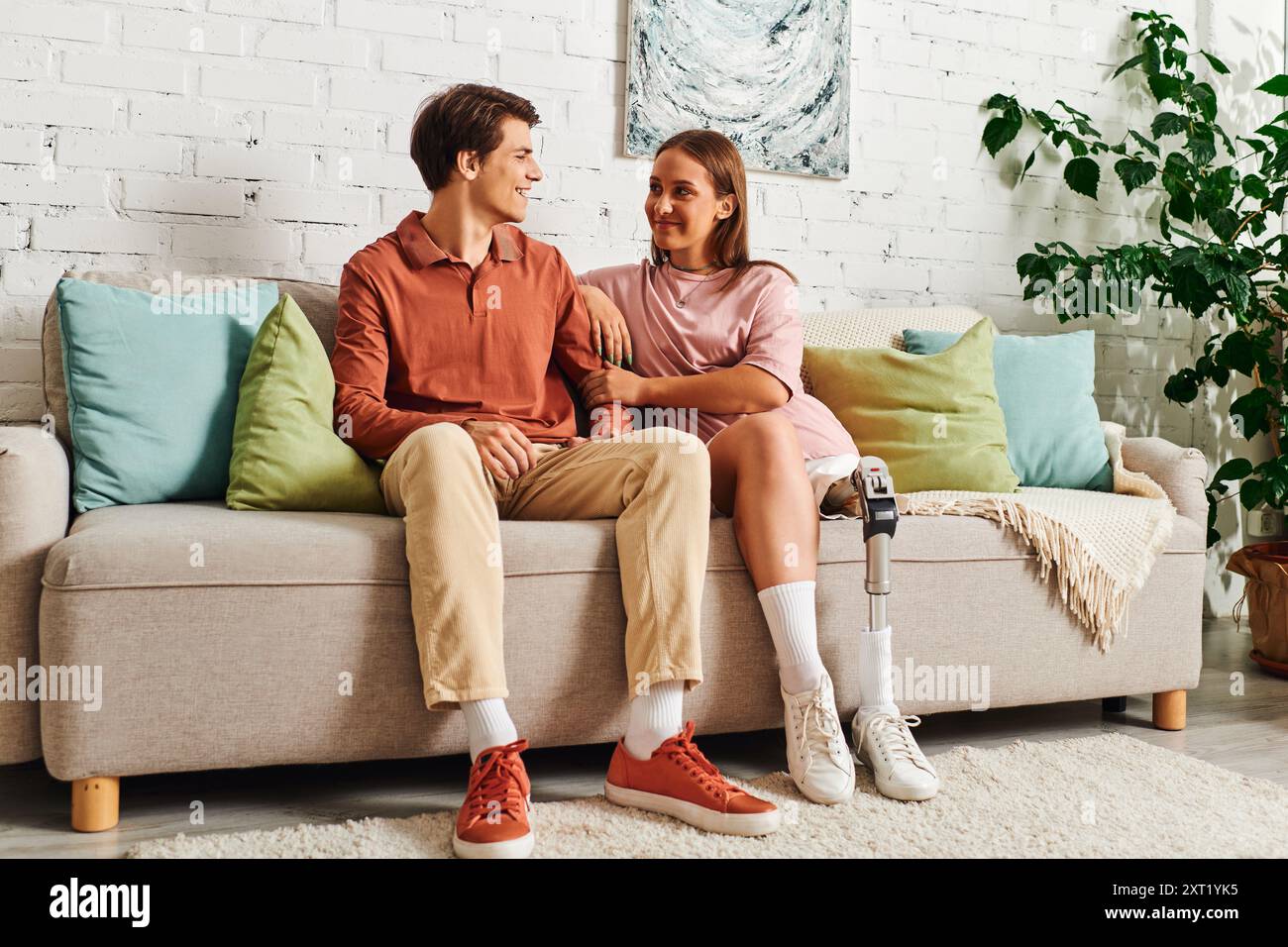 Young couple on couch gaze lovingly, woman has prosthetic leg Stock ...
