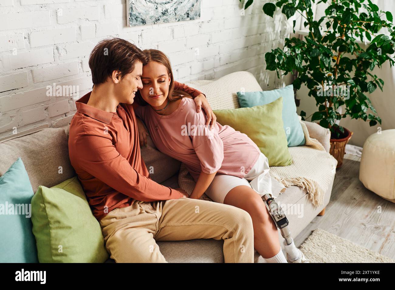 A couple relaxes on a couch, woman with a prosthetic leg, sharing ...