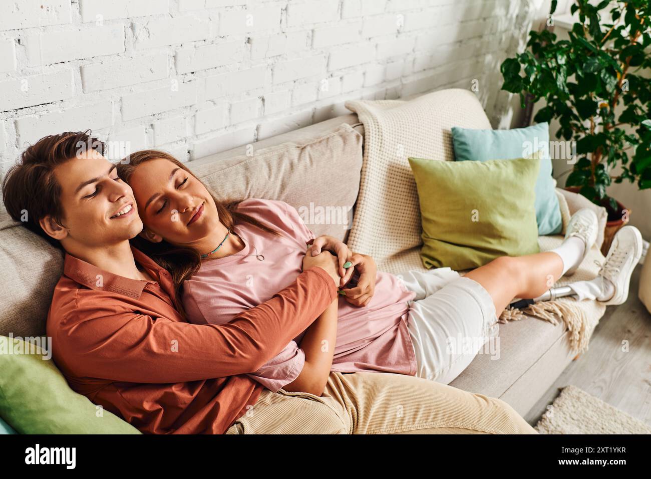 A couple relaxes on a couch, with the woman resting her head on her boyfriends shoulder Stock ...