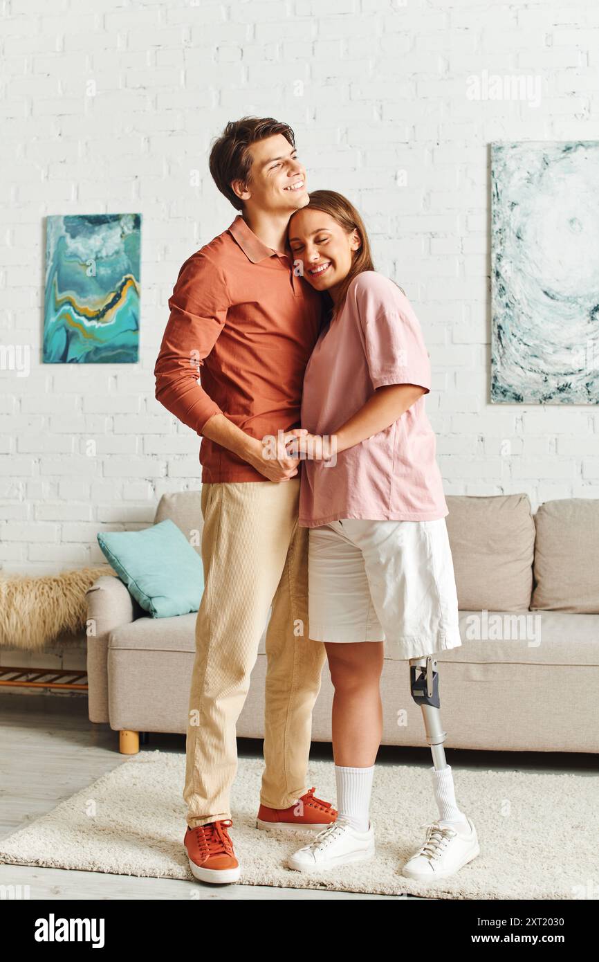 A young woman with a prosthetic leg hugs her boyfriend in their living ...