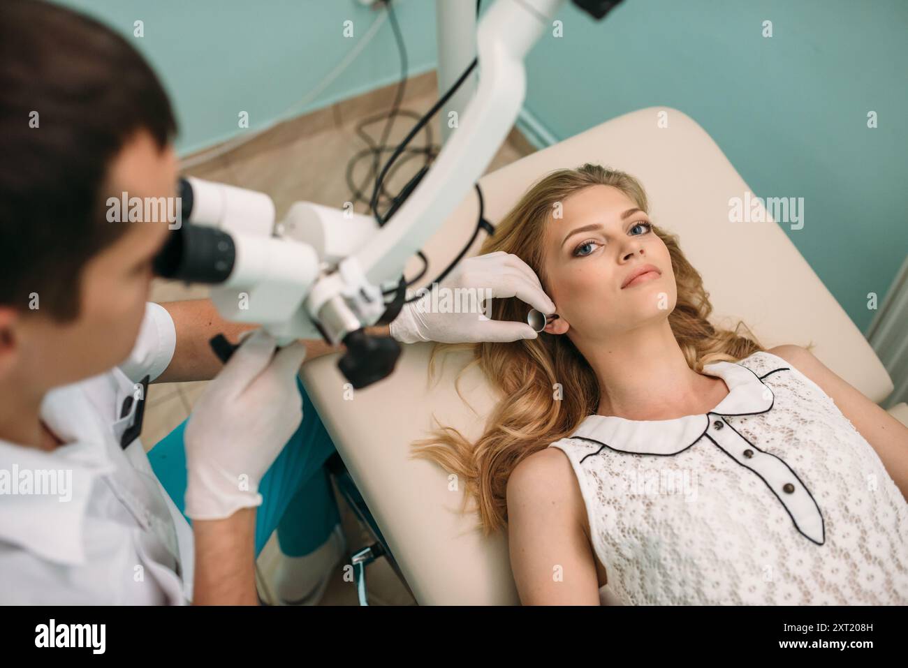 A clinician carefully examines a patient's ear using a microscope in a ...