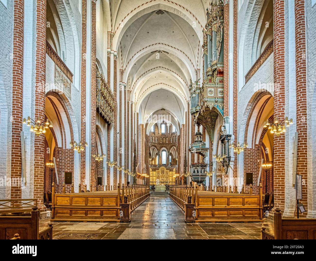 The Roskilde Cathedral interior with tall columns and golden altarpiece ...
