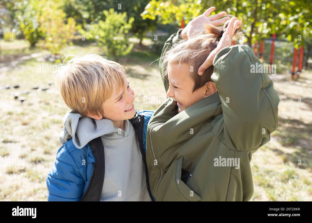 Two brothers or friends, 7-8 years old, looking at each other, hugging ...