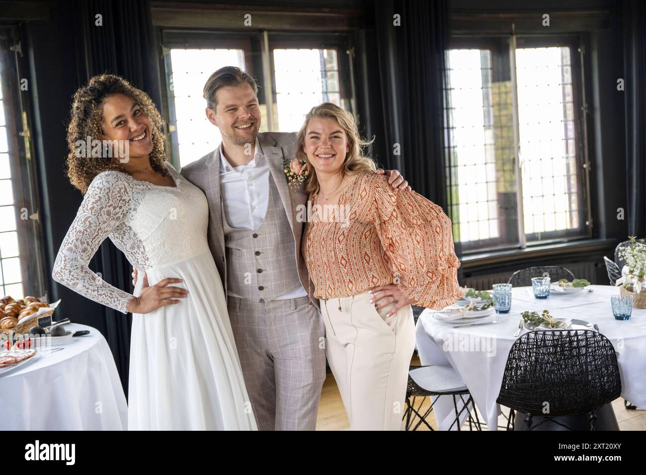 Three friends dressed in formal wear smile together at an elegant ...