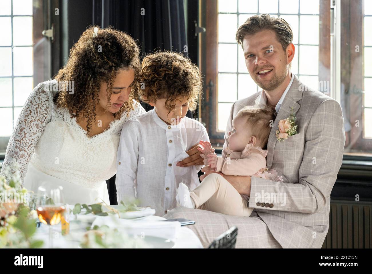 Family dressed in formal attire enjoys a moment together with a baby at ...