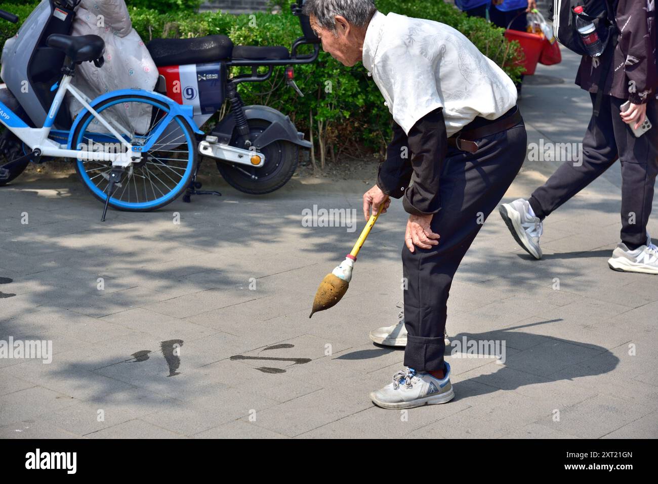 Man practicing water calligraphy (ground writing - dishu), popular ...