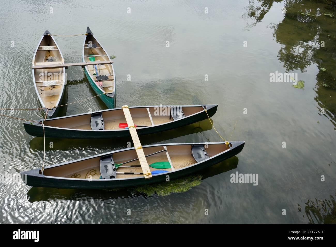 4 empty canoes tied up on a river Stock Photo - Alamy
