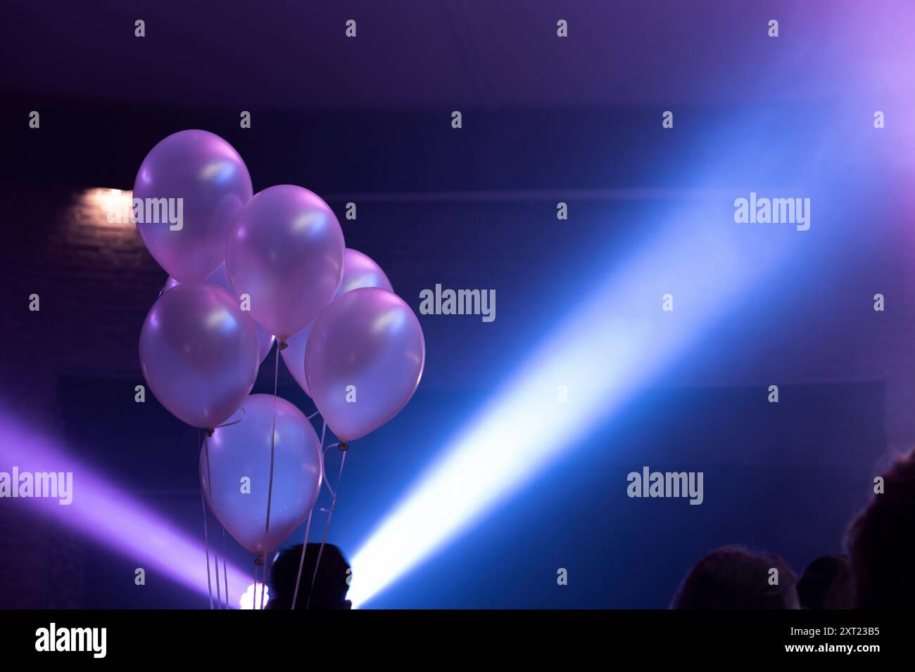White balloons illuminated by blue stage lights against a dark ...