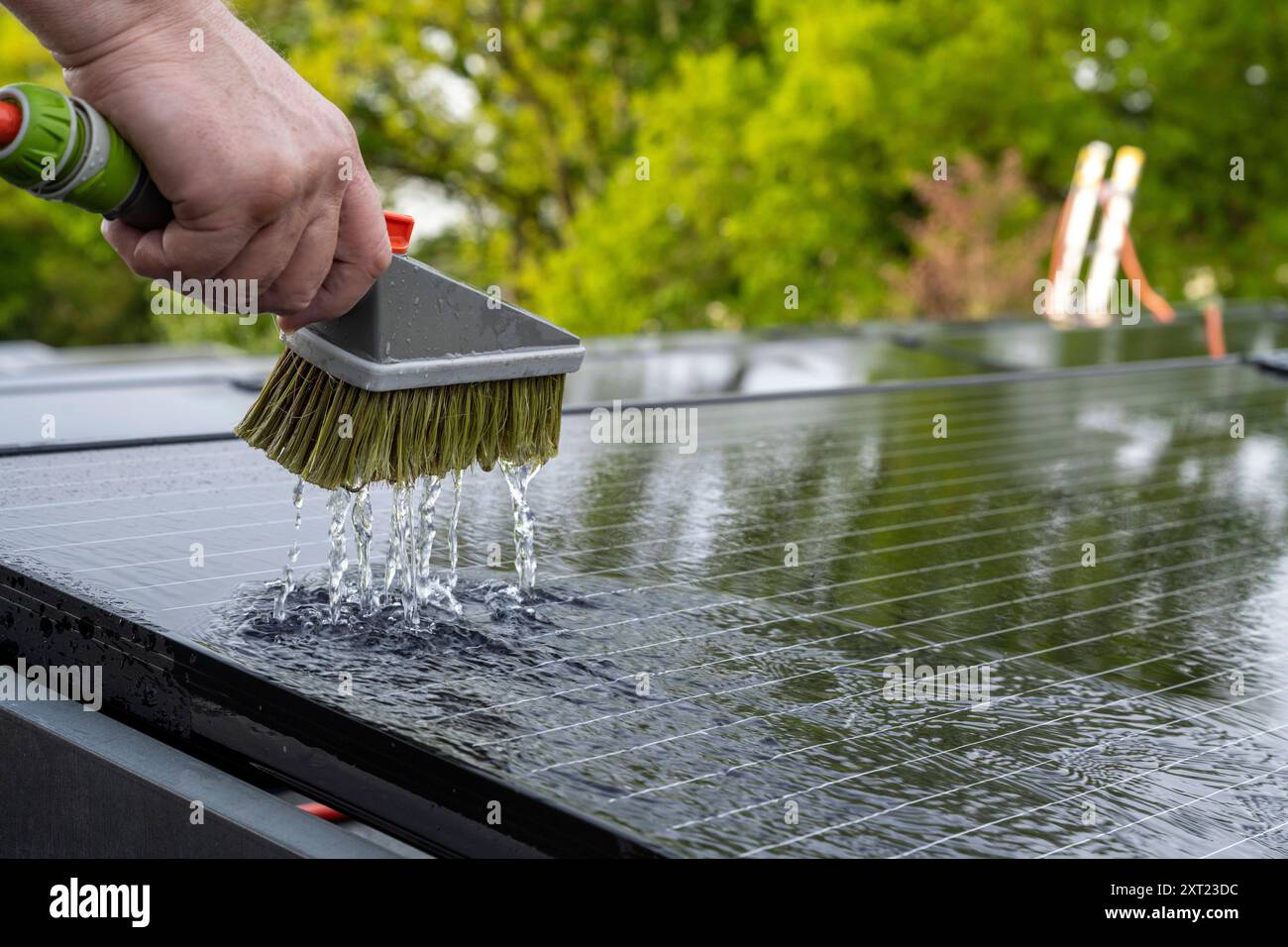 Zonnenpanelen op plat dak woonhuis reinigen Close-up of a hand using a ...