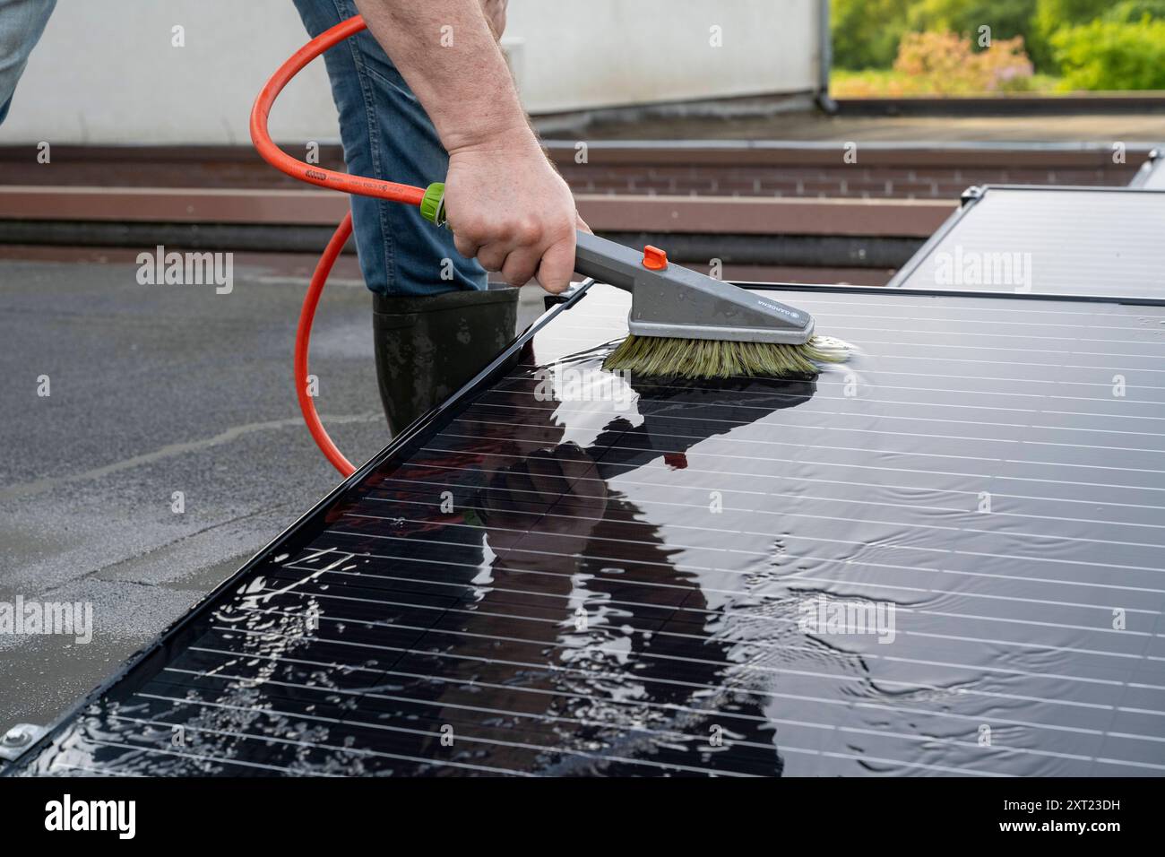Zonnenpanelen op plat dak woonhuis reinigen A person cleaning a solar ...