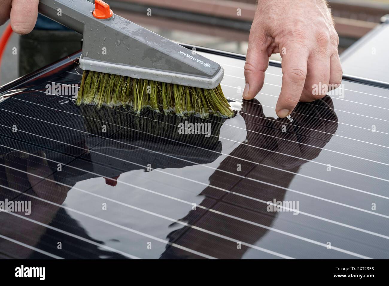 Zonnenpanelen op plat dak woonhuis reinigen Hand with a brush cleaning ...