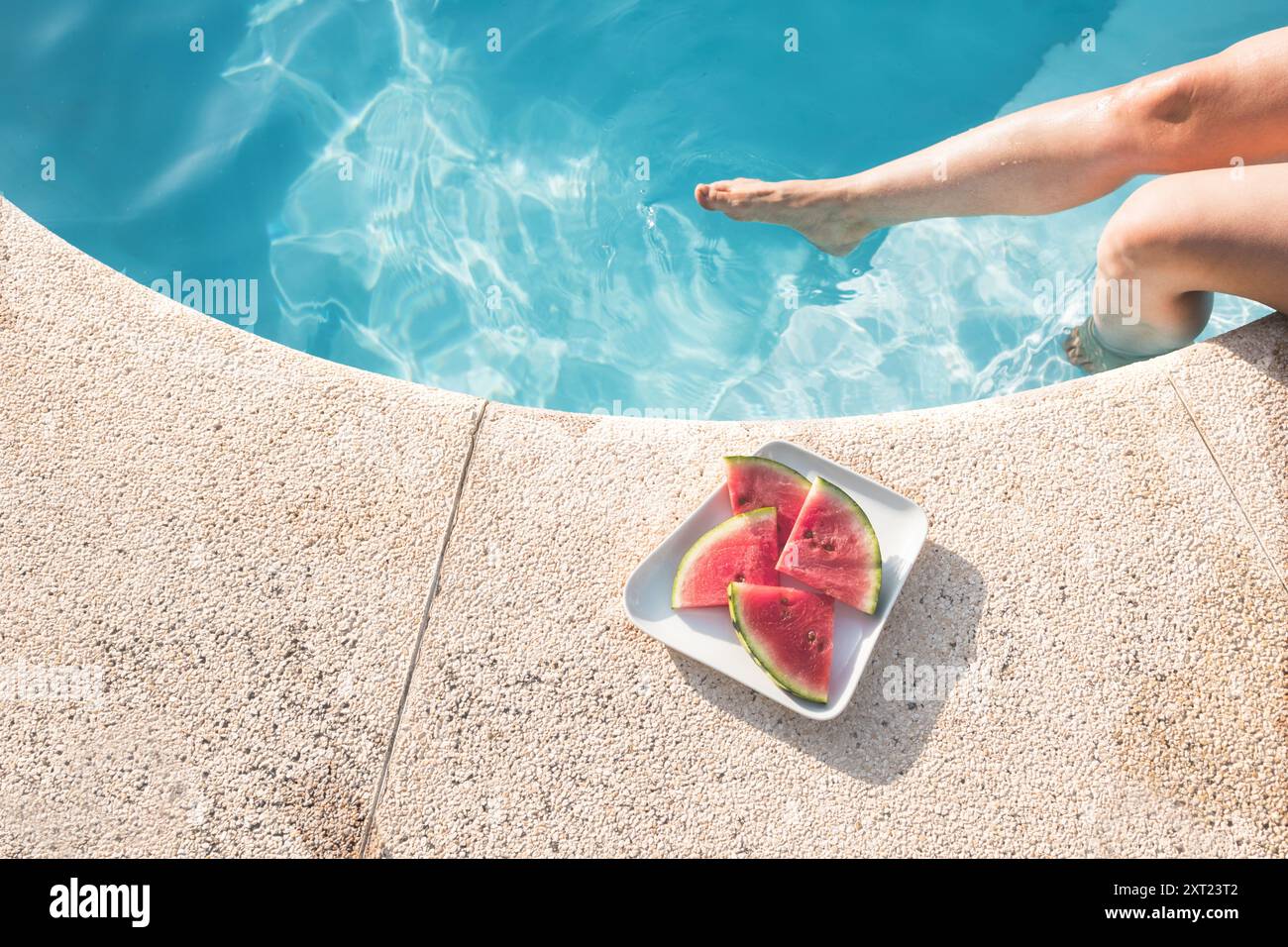 A leg dipped in the pool while lounging next to a plate of watermelon ...