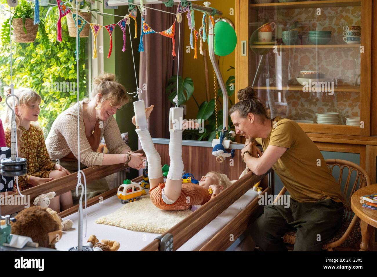 A family enjoys a playful moment in a cozy kitchen with a child in a ...