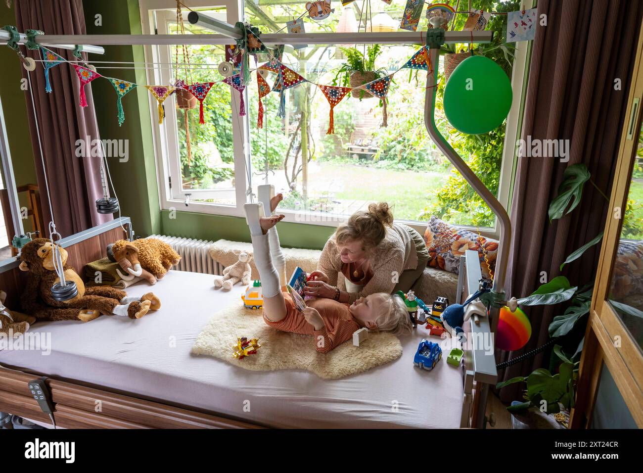 Mother caring for her injured child with cast on their legs. laying in ...