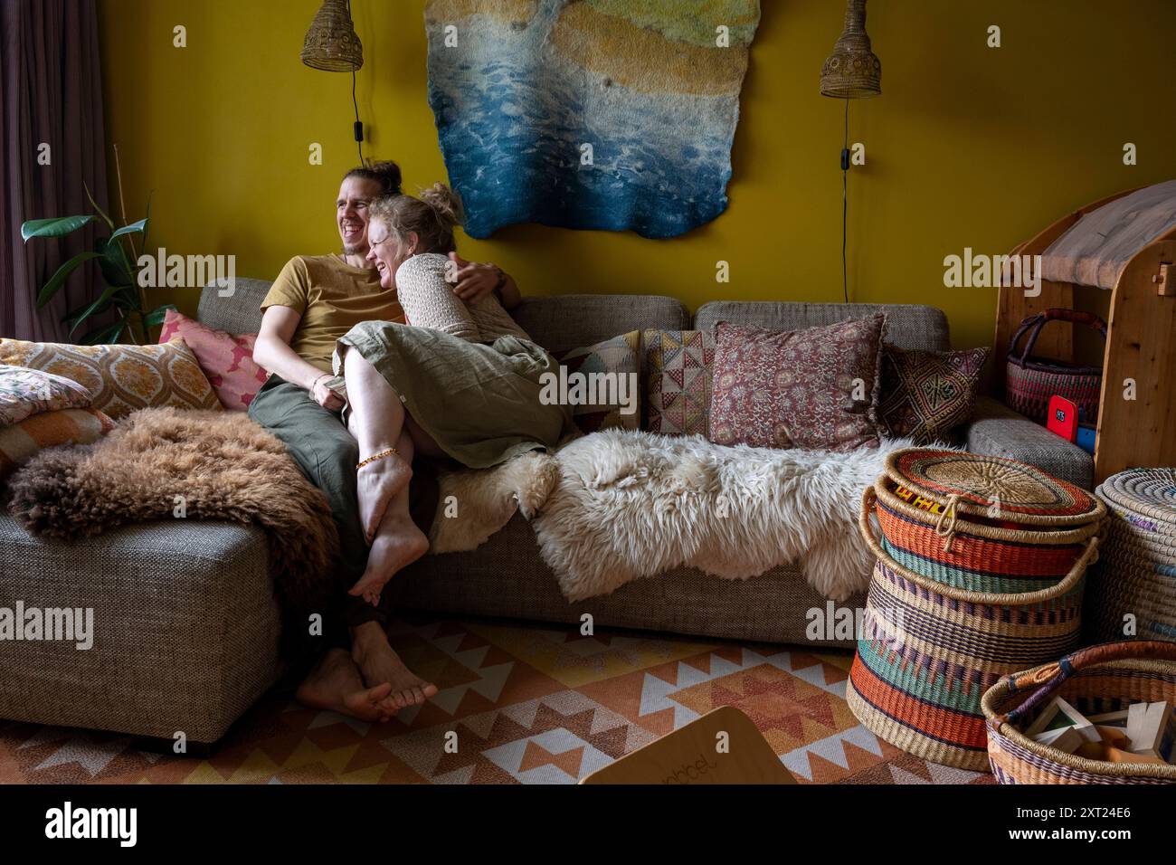 Two people laughing and embracing on a cozy sofa in a warmly decorated ...