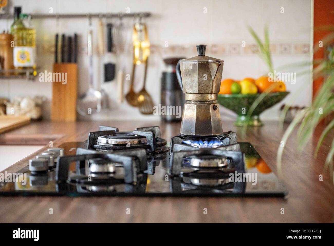Stainless steel espresso maker on a gas stove with blue flames in a ...