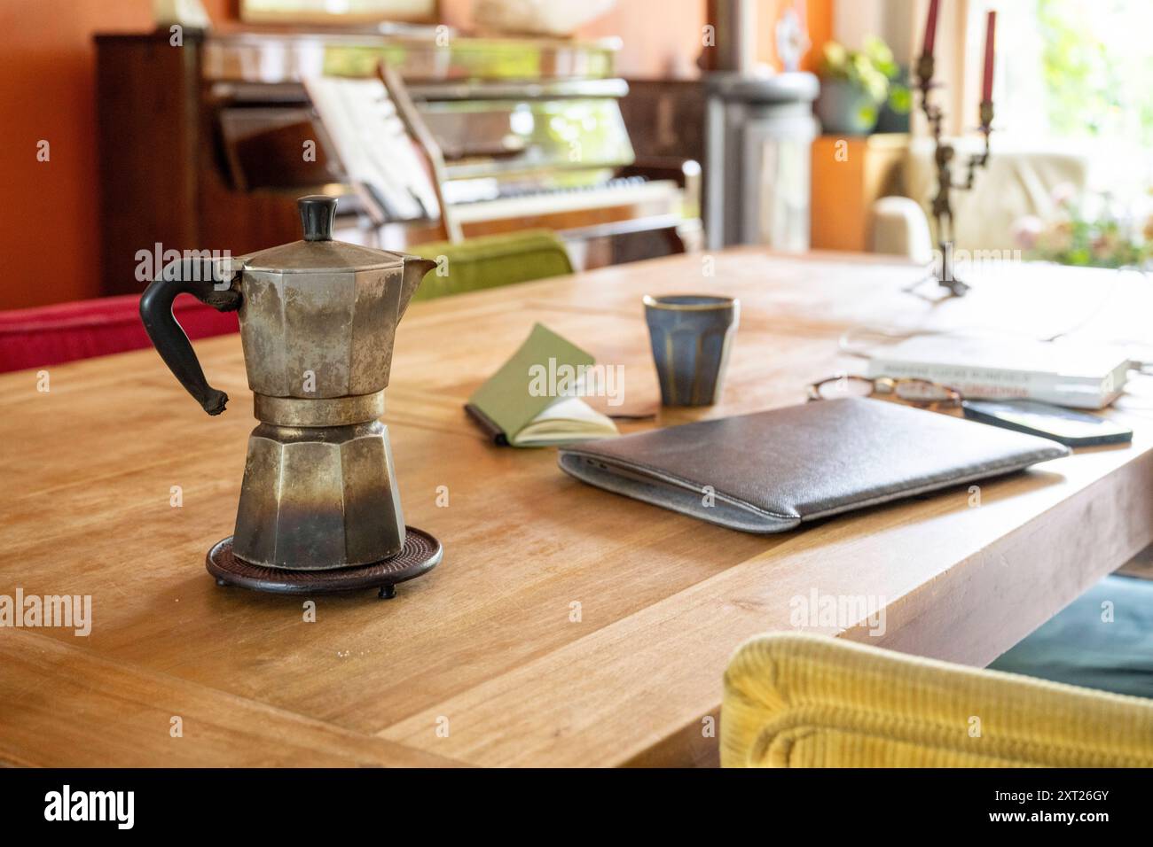 An old-fashioned moka pot on a wooden kitchen table, surrounded by a ...