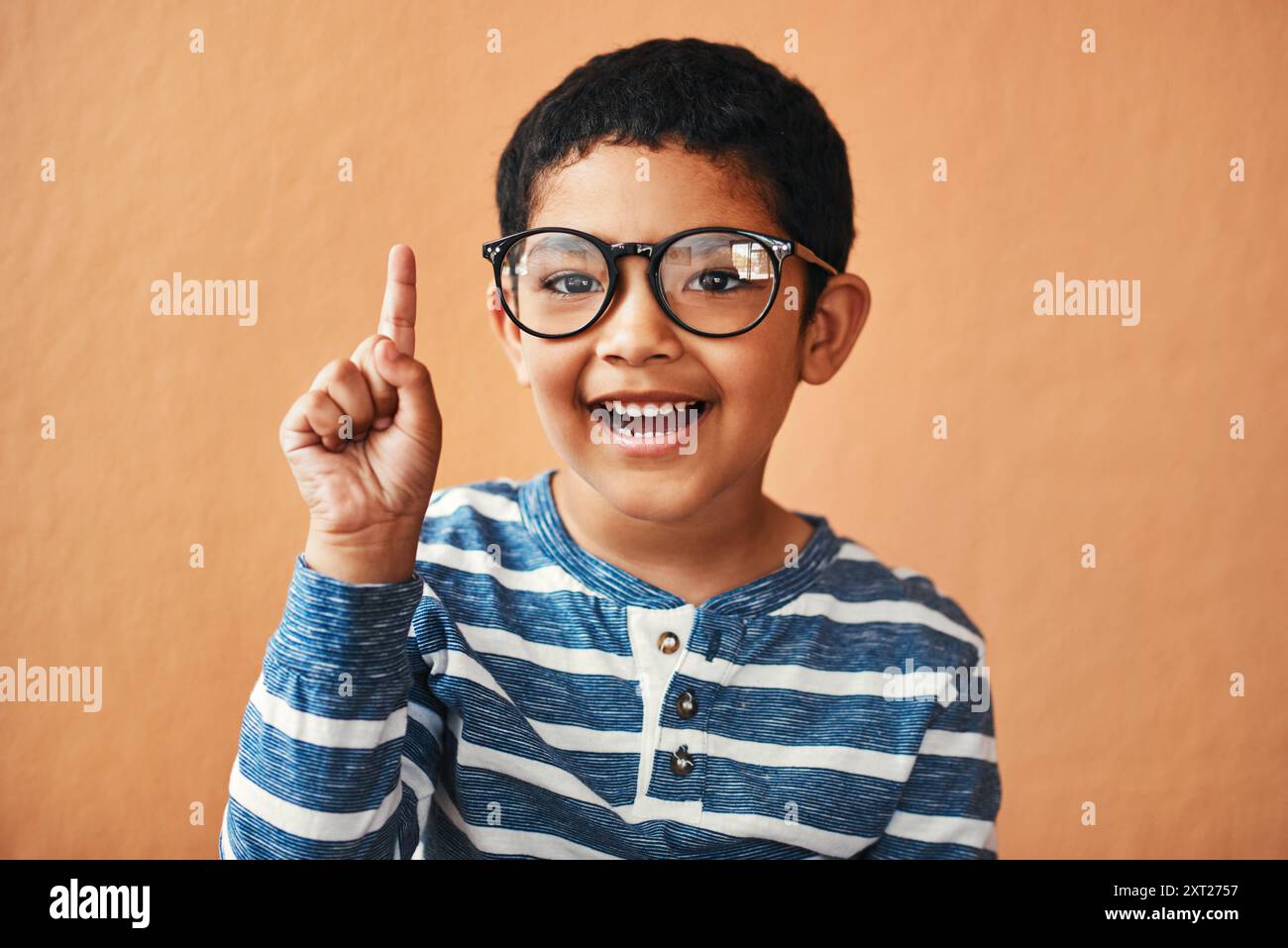Child, glasses and portrait with hand raised in studio for knowledge ...