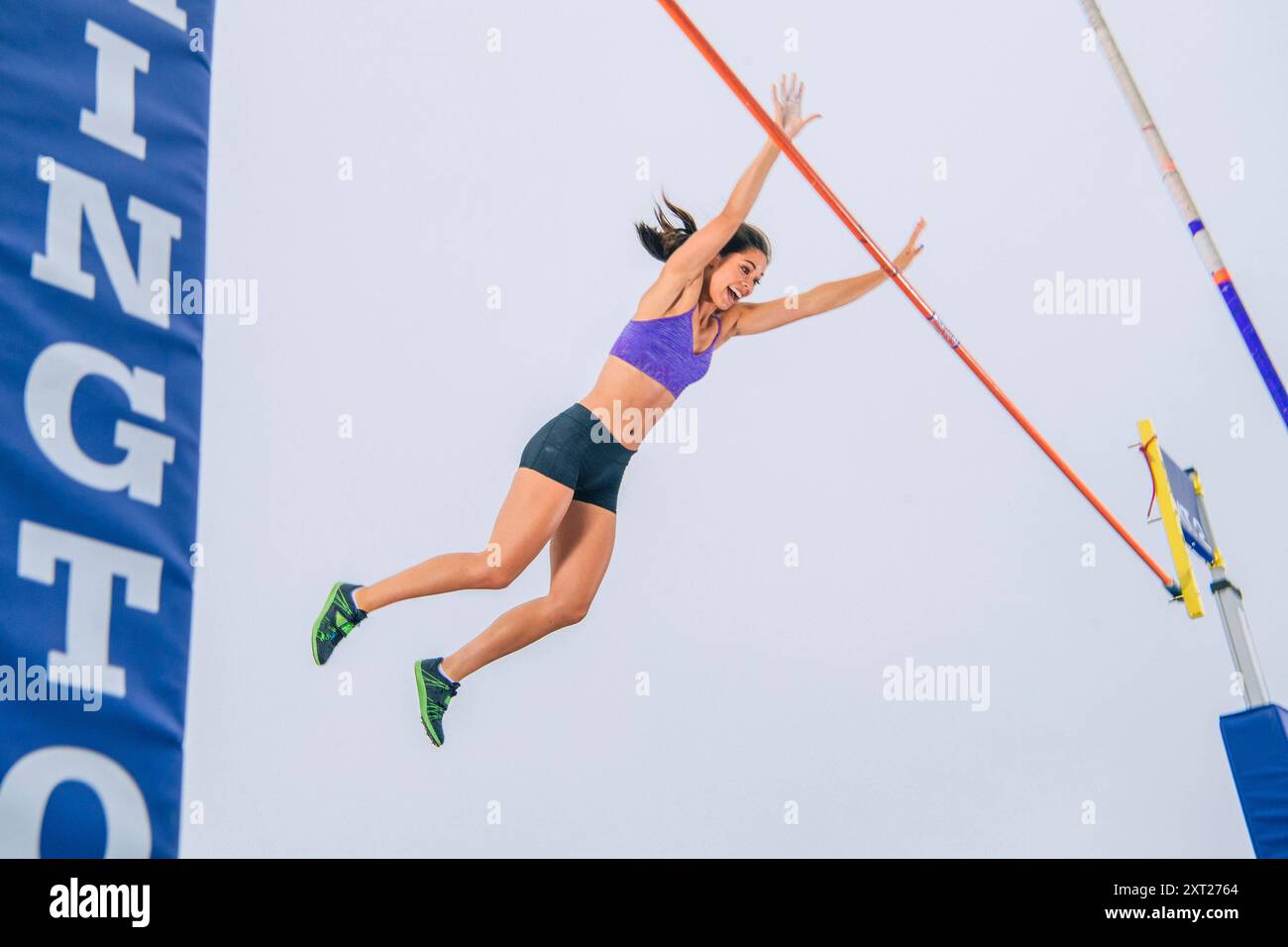 Female athlete jumping over a high bar in a pole vaulting competition ...