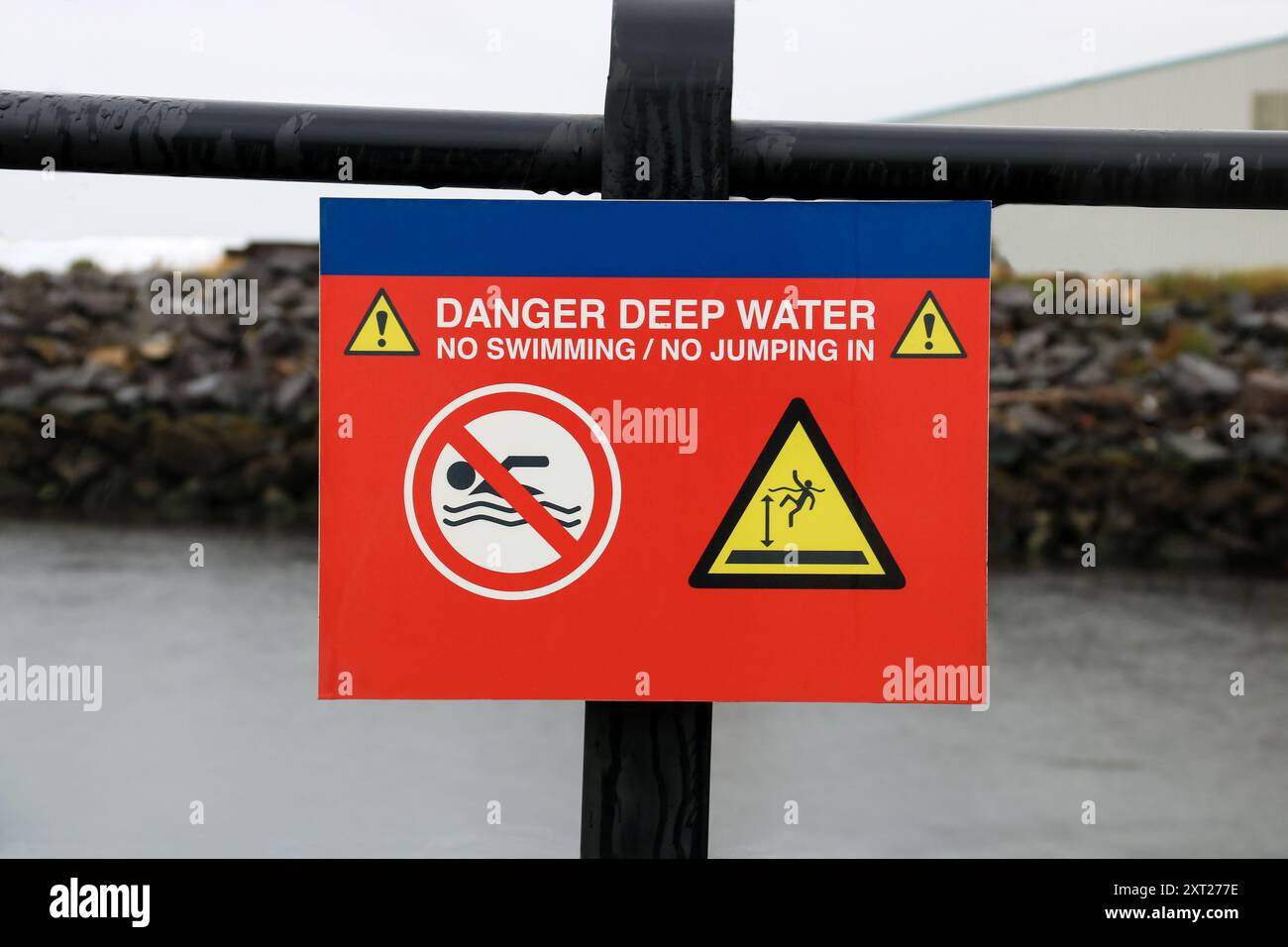 No swimming deep water warning sign at a coastal jetty on a rainy ...