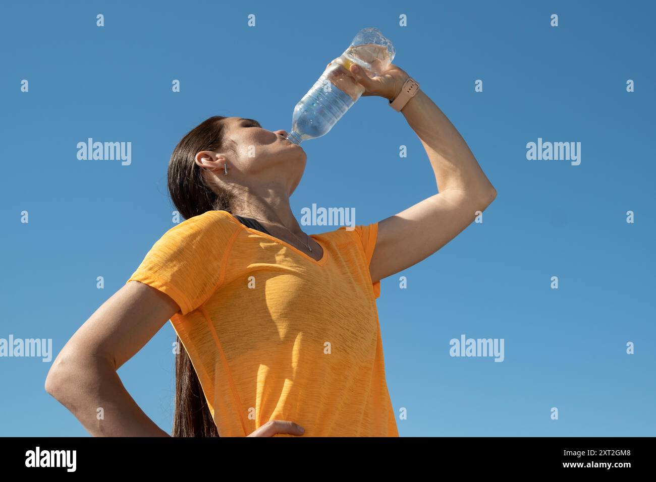 Low angle view of female sportsman drinking water from bottle. Woman ...