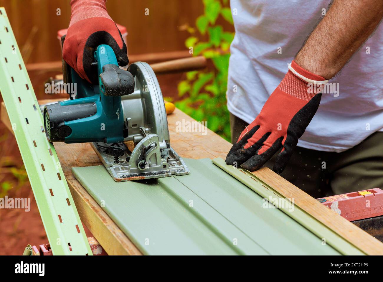 Worker cut plastic vinyl siding to size using circular handsaw before ...