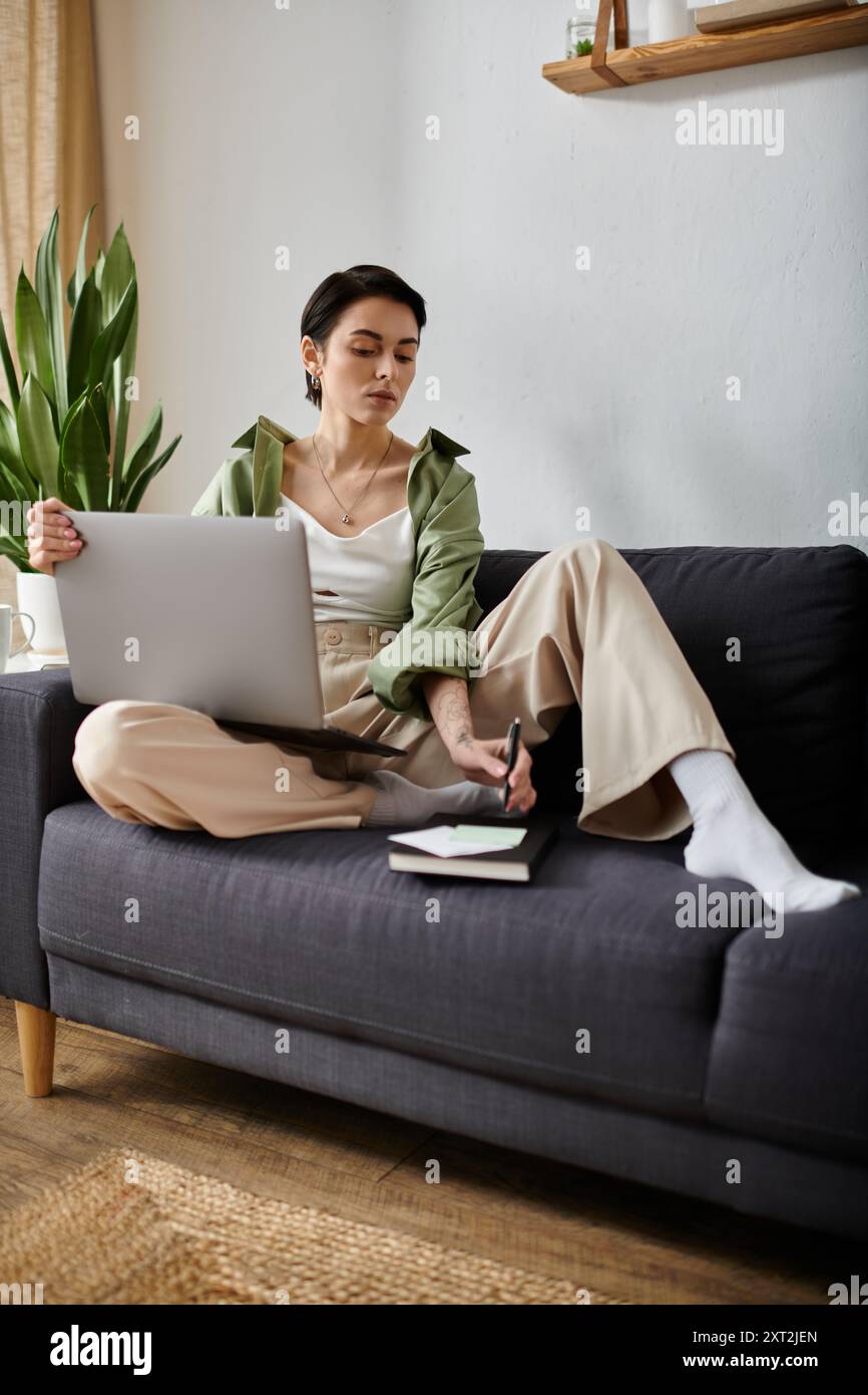 A woman works on her laptop while sitting on a couch in a comfortable ...