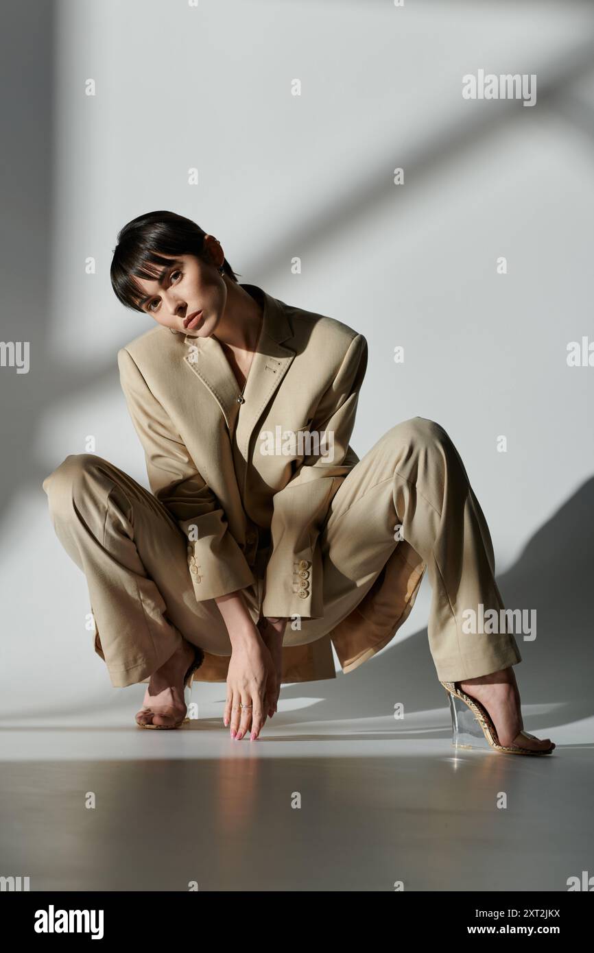 A woman in a tan suit poses in a studio with dappled sunlight Stock ...