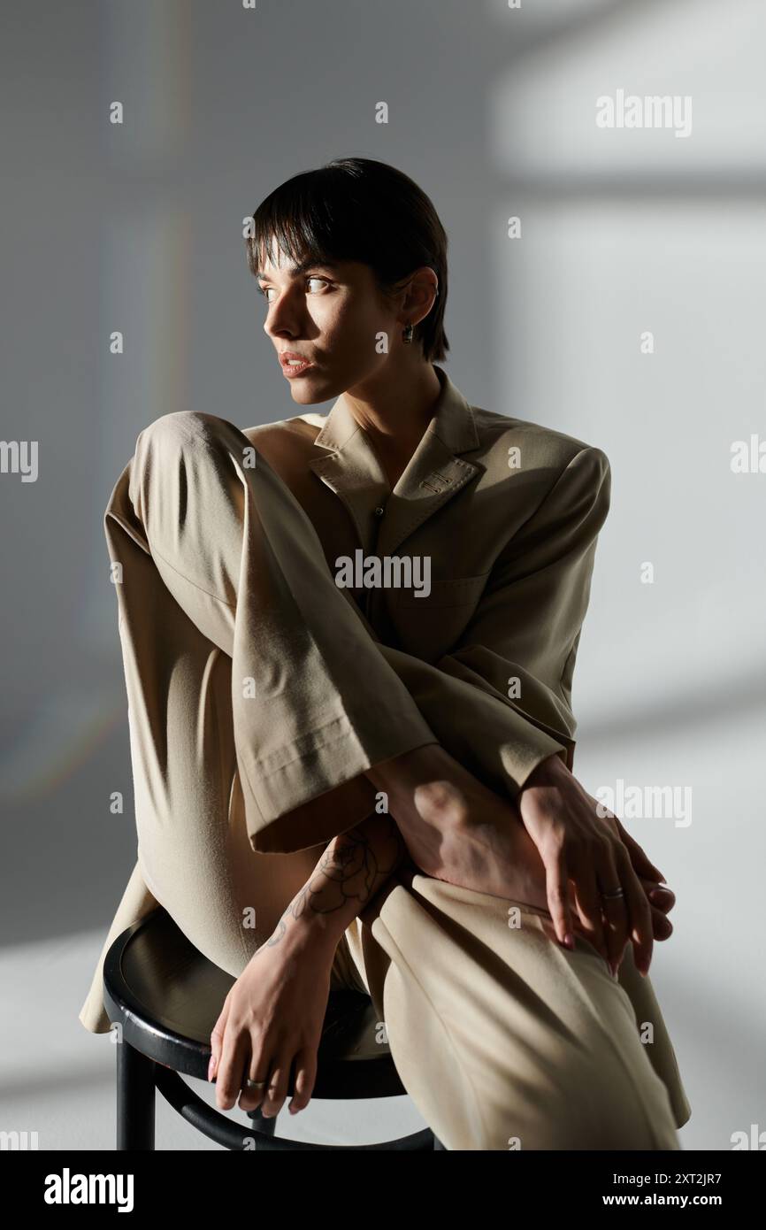 A woman poses in a beige suit with dramatic lighting Stock Photo - Alamy