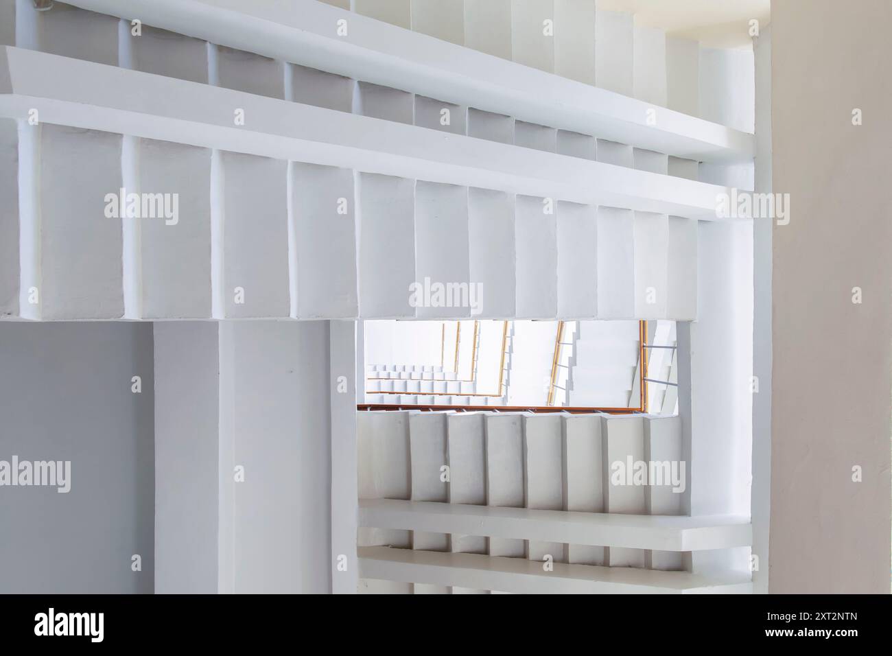 Looking up at a white spiral staircase with wooden handrails and metal ...