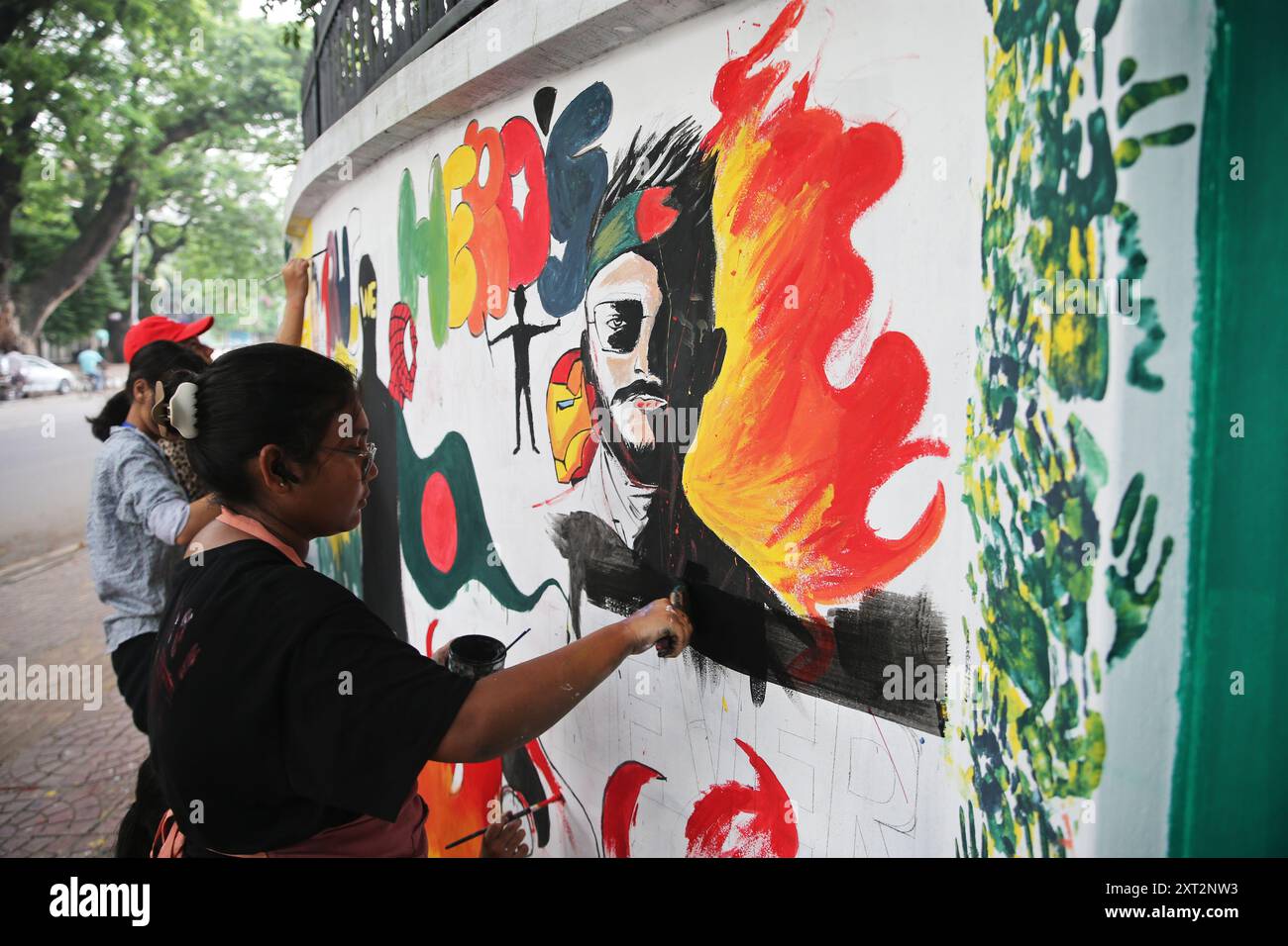 A student paints a new graffiti on a street wall at Dhaka University ...