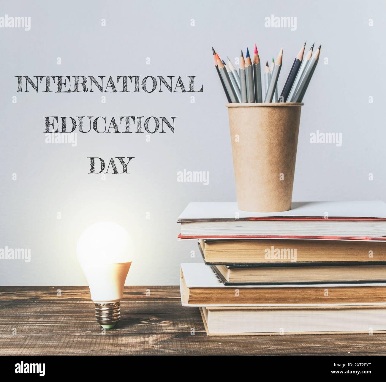 A light bulb is lit up next to a stack of books and a pencil holder ...