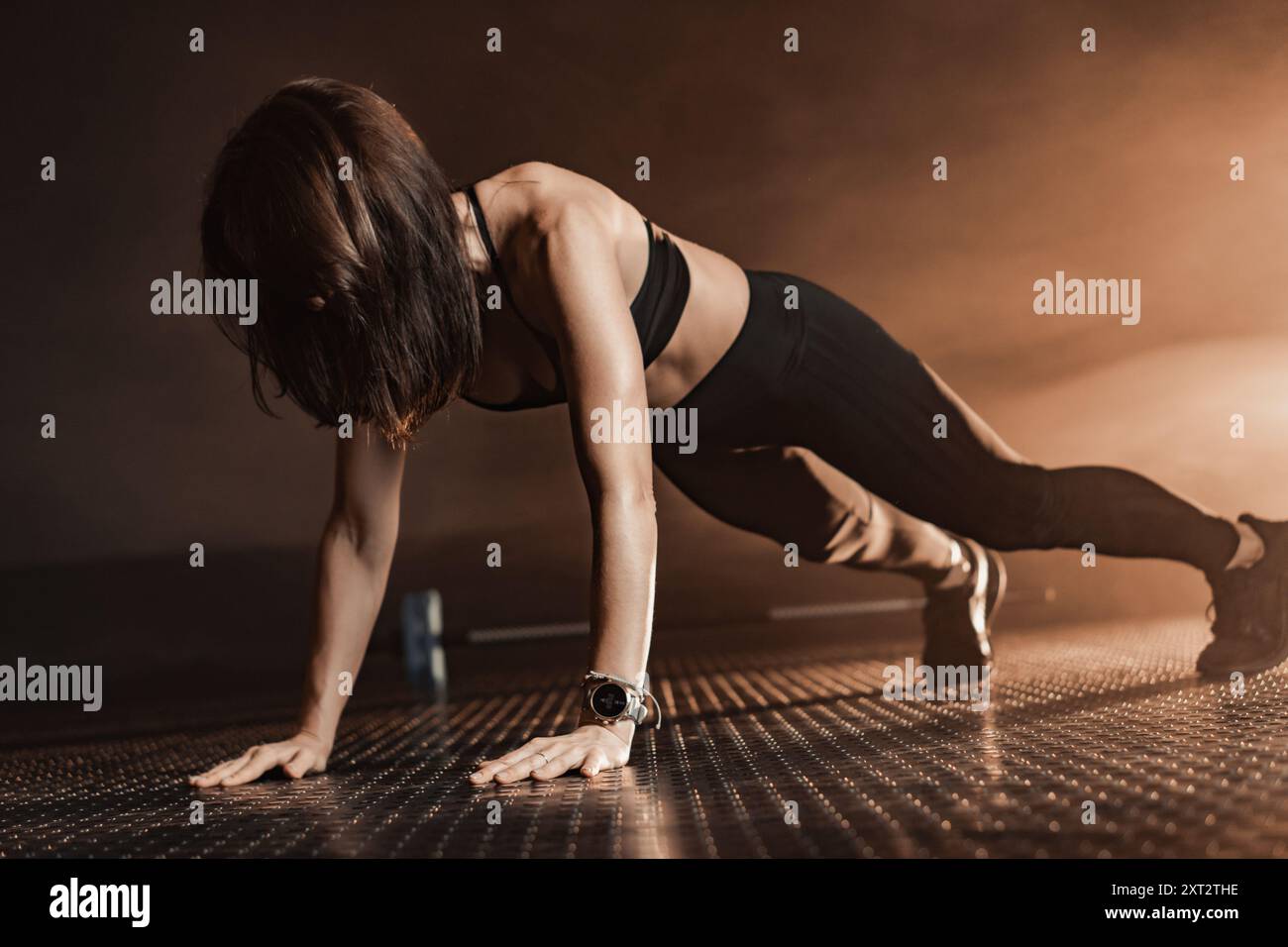 A dedicated female fitness model is engaging in a powerful pushup ...