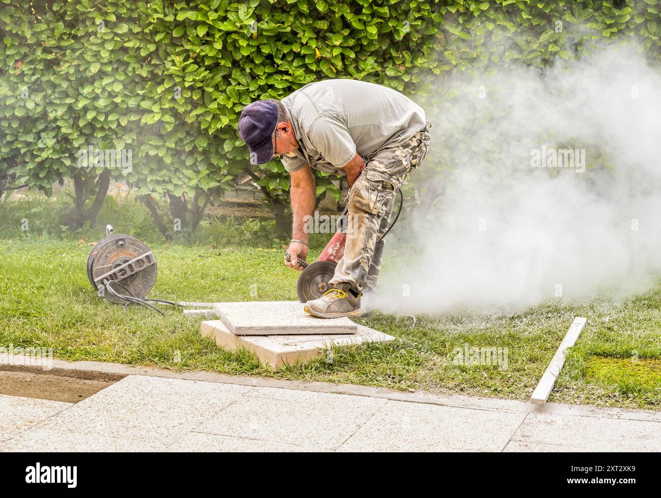 Worker cutting concrete slabs for floor with circular electric saw ...